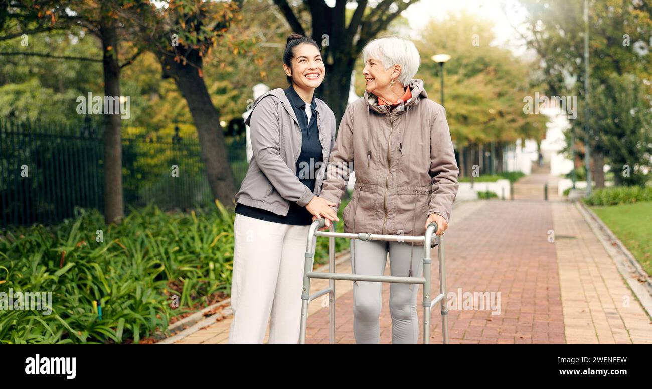Senior woman, walker and nurse outdoor in a park with healthcare for ...