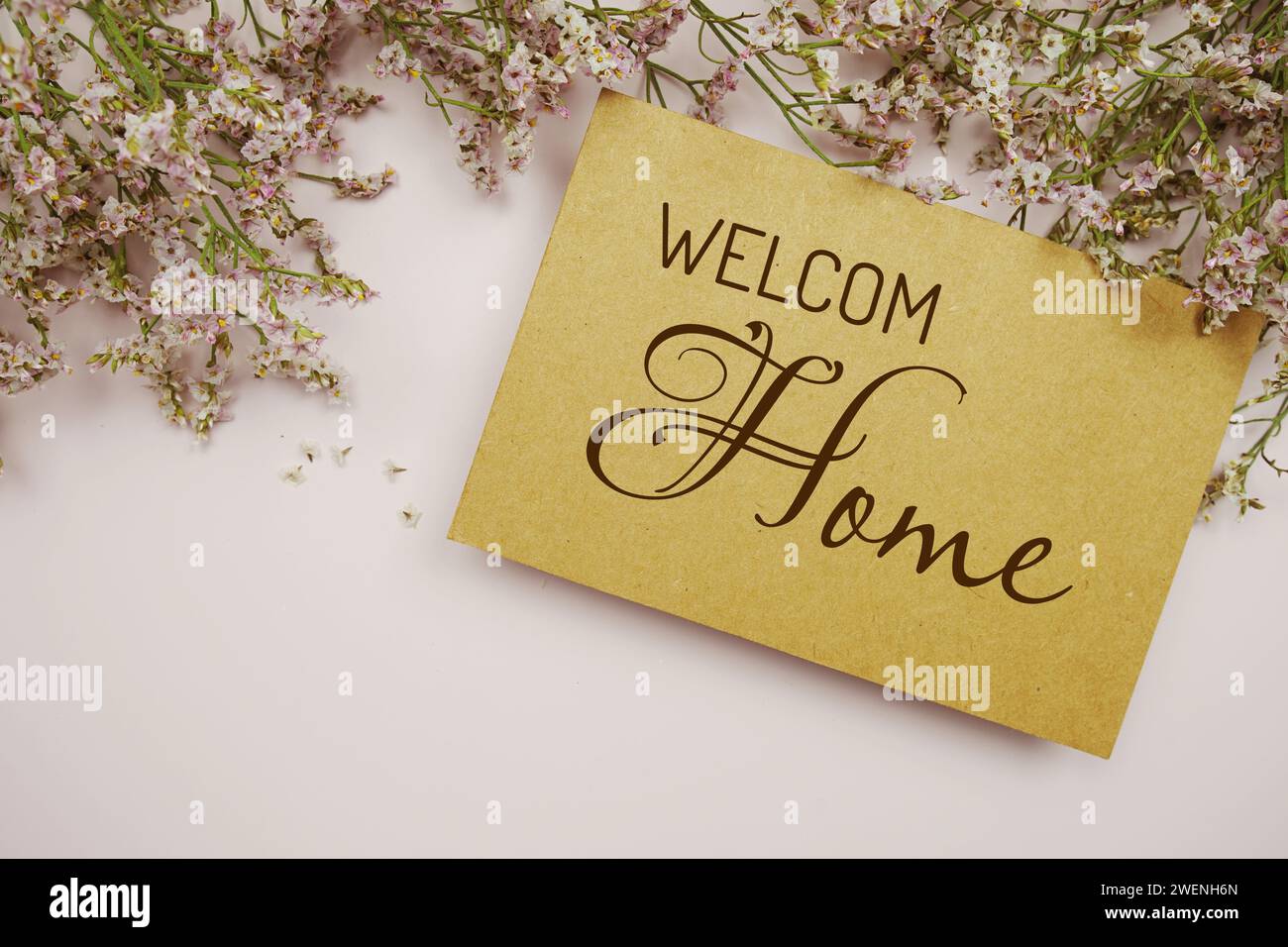 Welcome Home written on paper card with flower frame decoraton on pink ...
