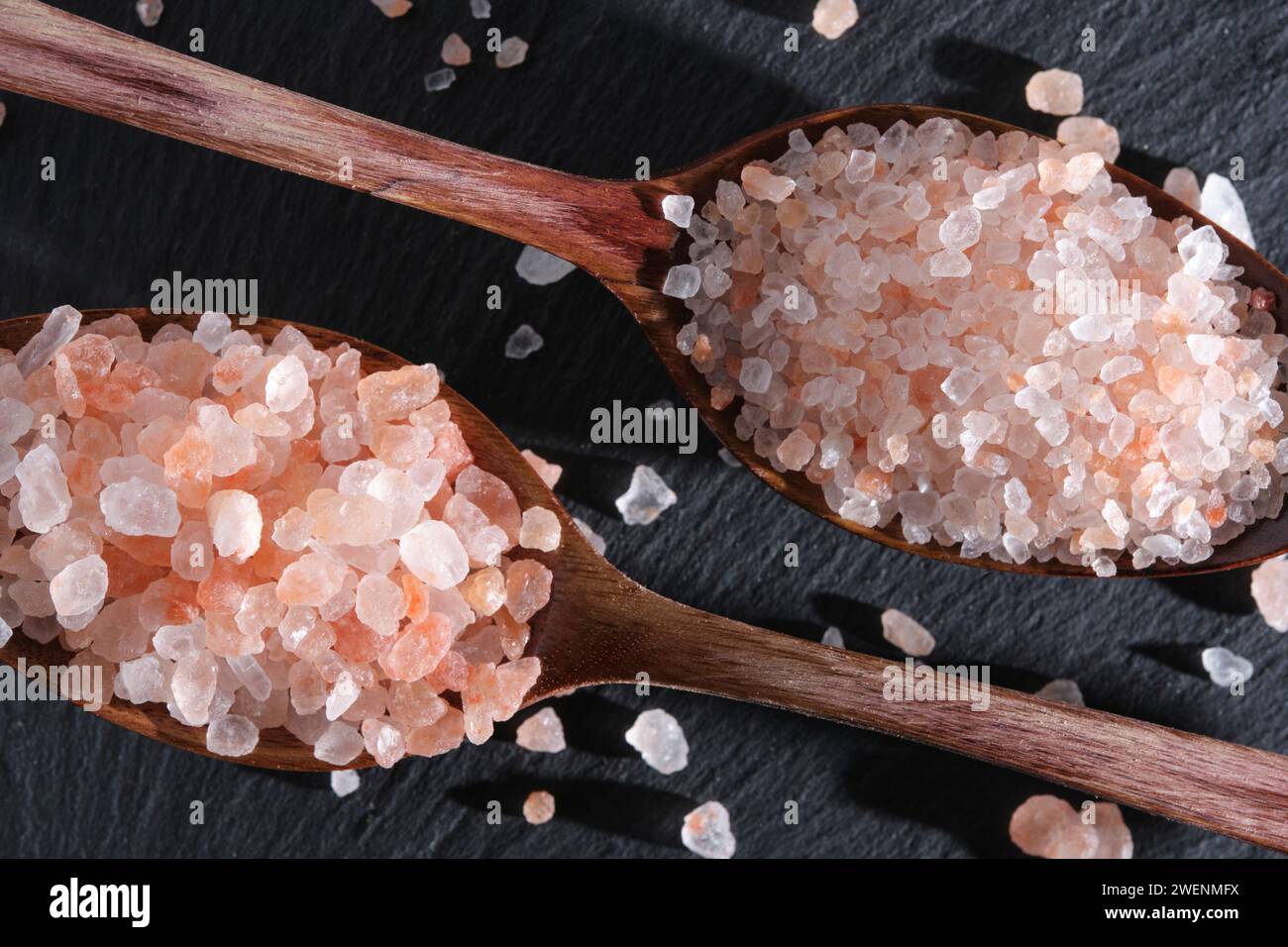 Two wooden spoons lying on a slate are filled with pink salt Stock ...
