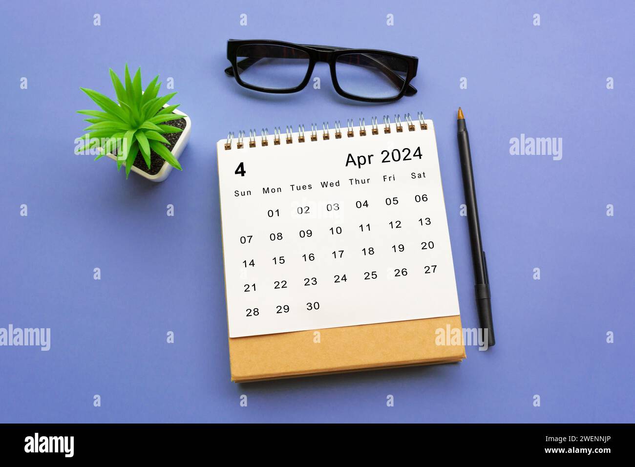 April 2024 desk calendar on blue background Stock Photo - Alamy