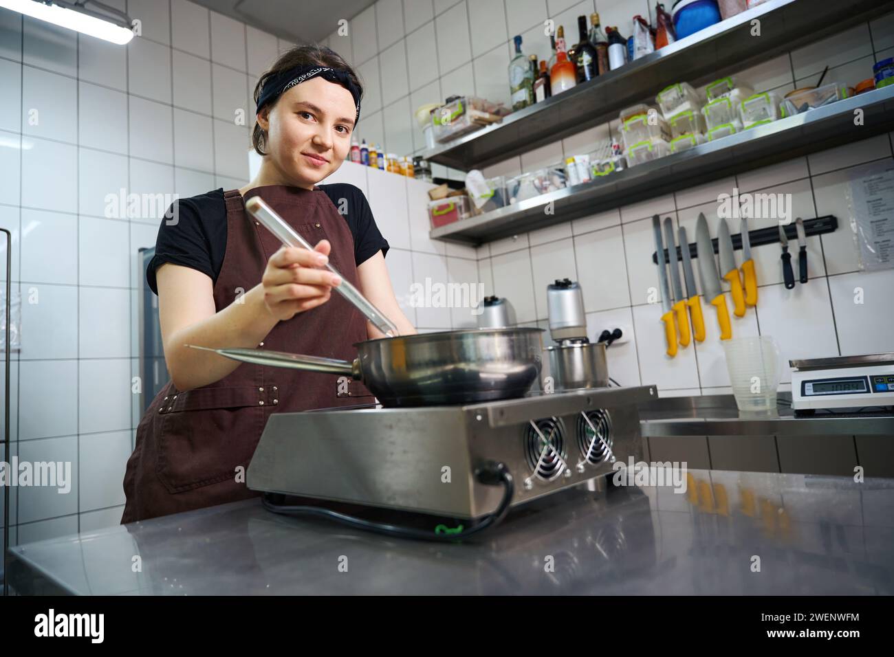 Contented young cook measuring food temperature while cooking Stock ...