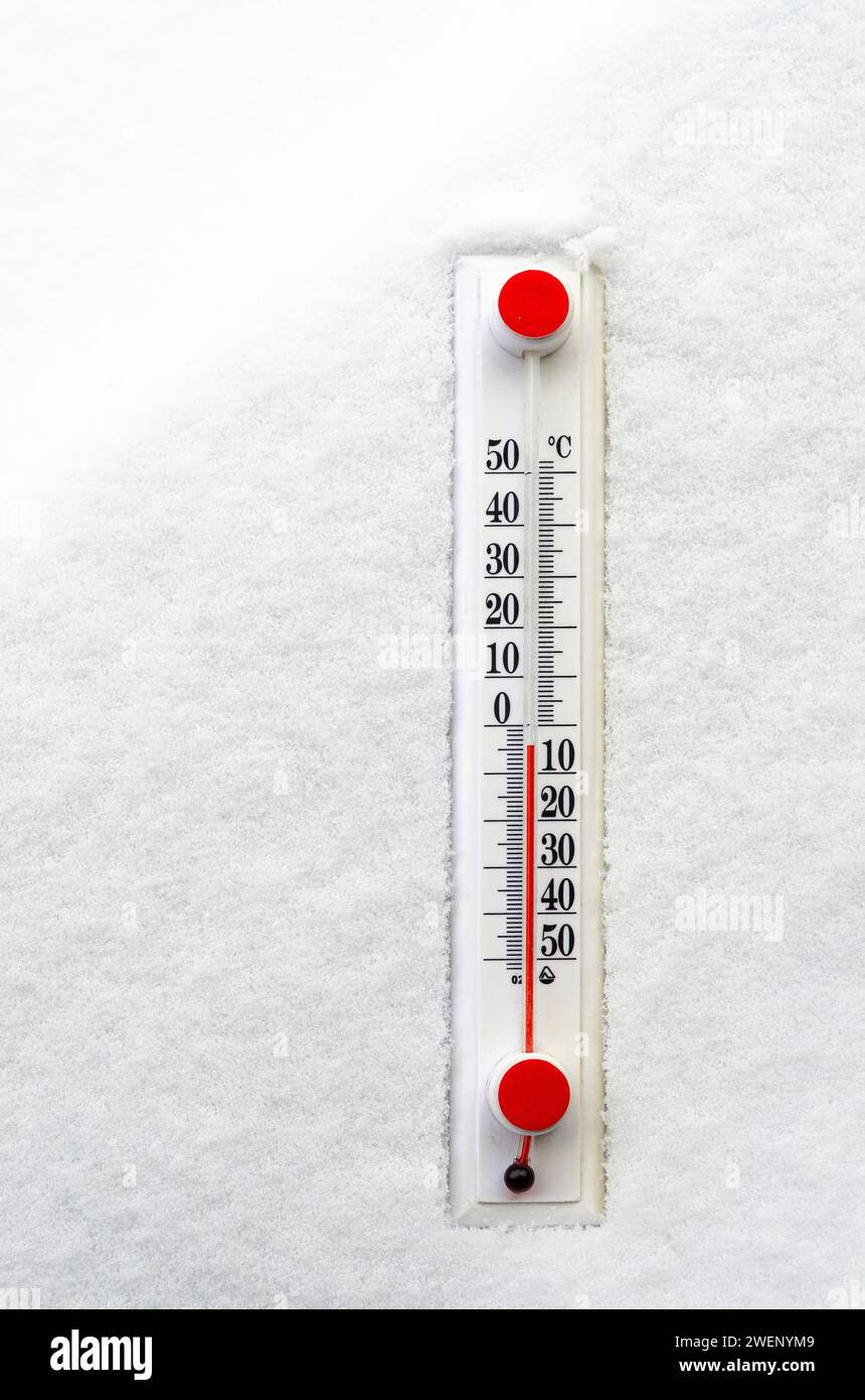 Temperature. A white thermometer with a red scale lies on white snow ...