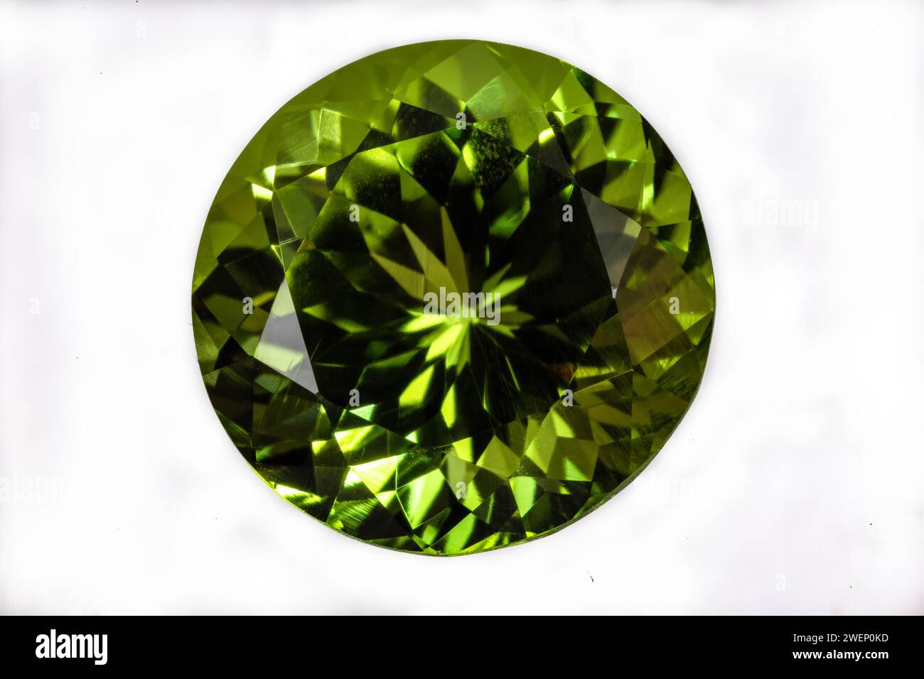 Green faceted peridot gemstone. Round, brilliant cut. White background ...