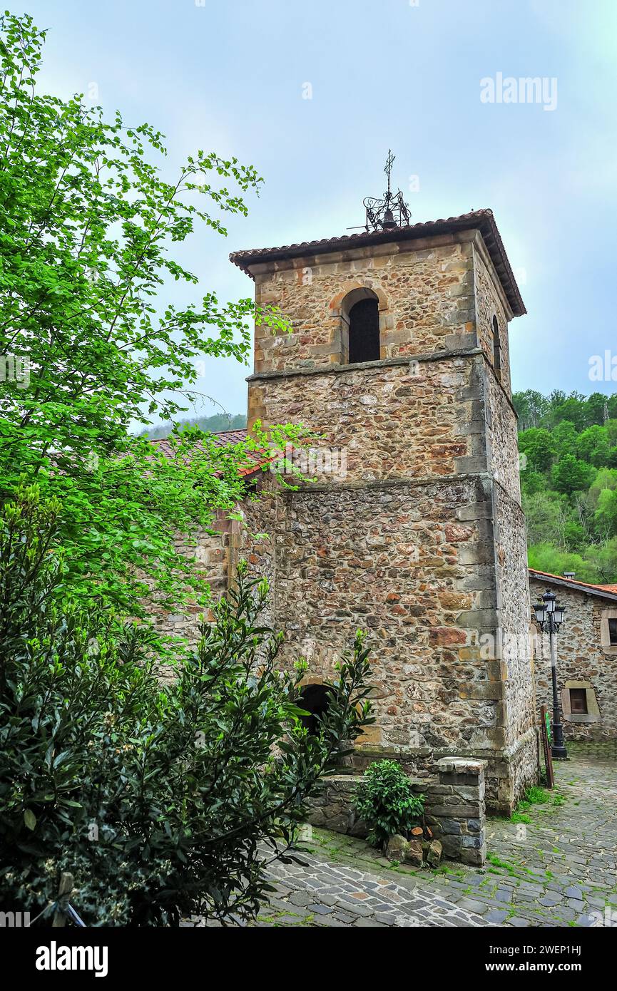 An ancient stone bell tower rises above the foliage in a historic ...