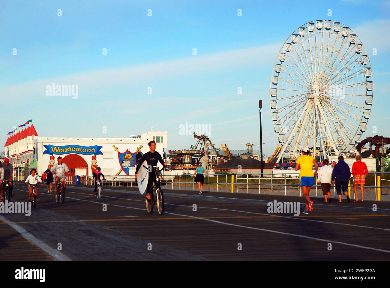 An adult man rides his bicycle while carrying his surfboard in the ...