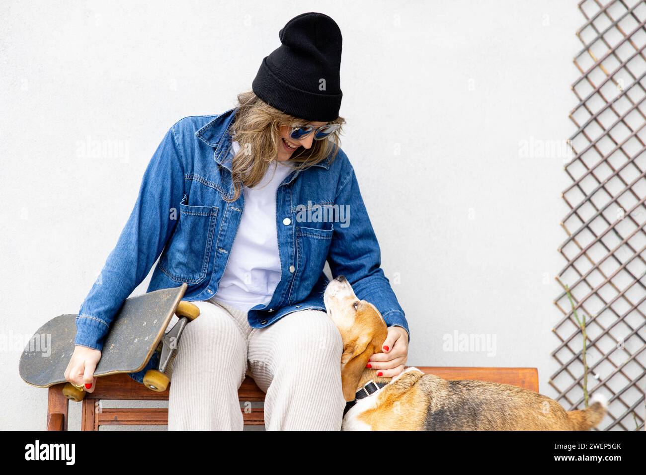 "A cheerful young woman in a denim jacket and beanie enjoys a playful ...