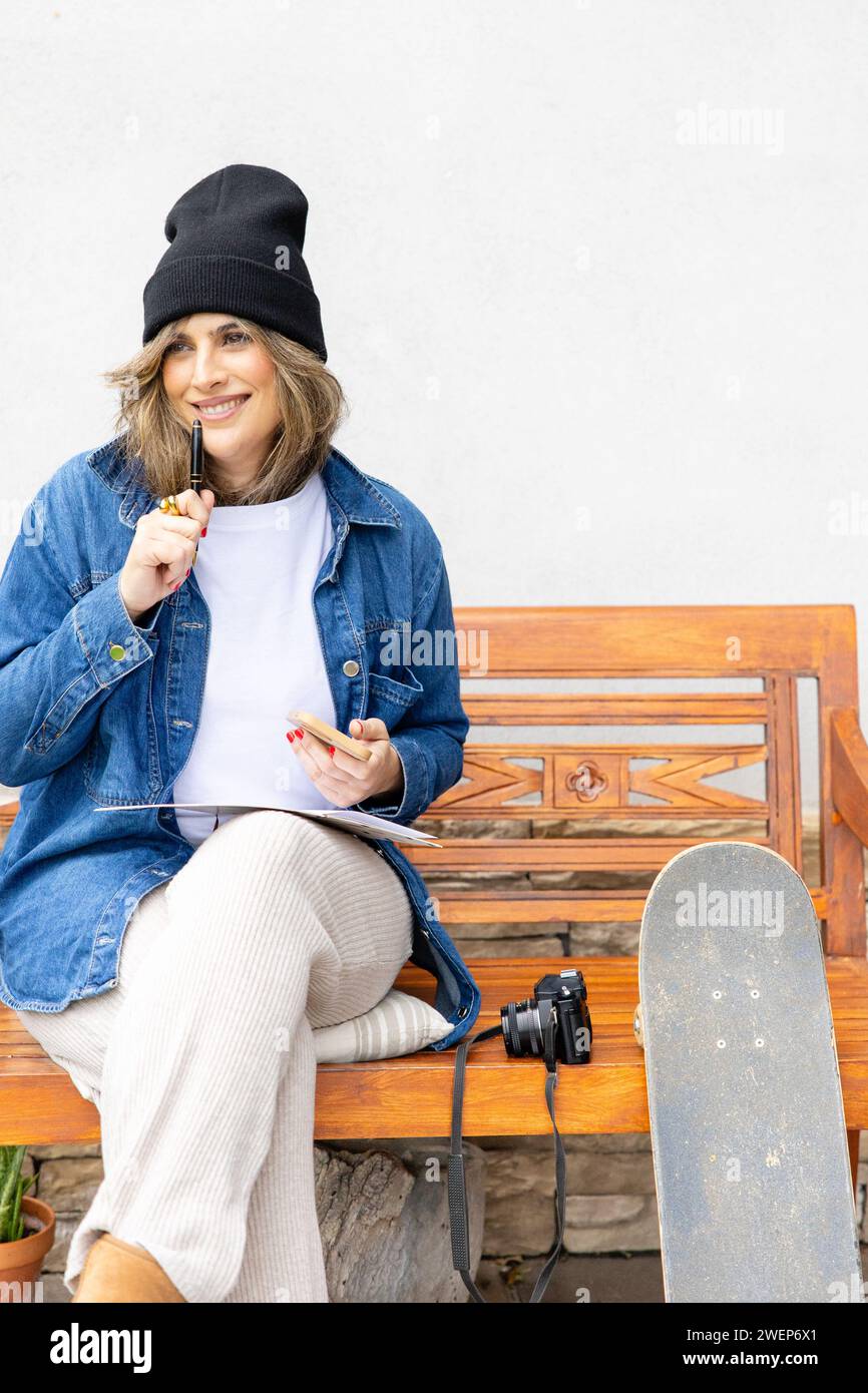 Smiling artist enjoys a creative break outdoors, with a pen in hand and ...