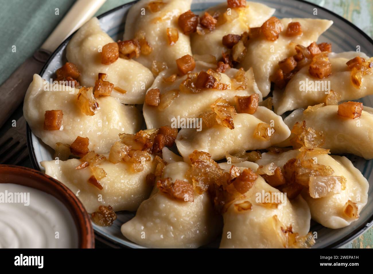 Traditional Ukrainian food - dumplings varenik with sour cream close up. Fried bacon and onion ...