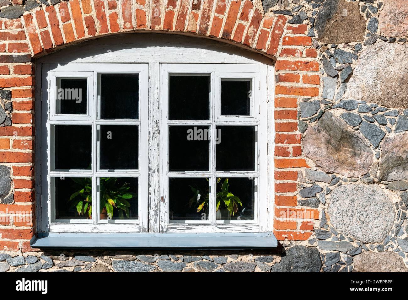 Window with a frame covered with old weathered paint, on a stone wall ...