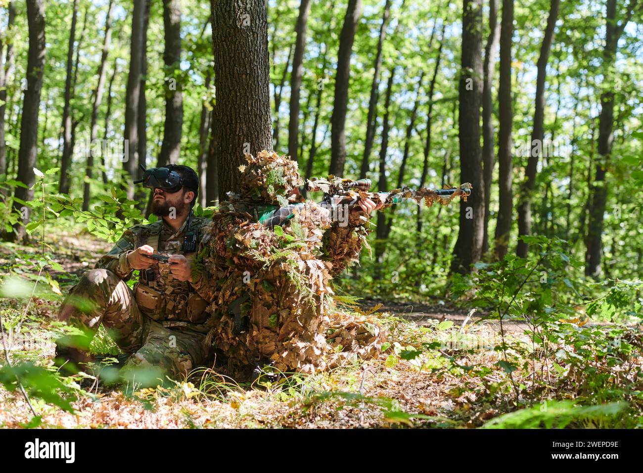 A skilled sniper and a soldier operating a drone with VR goggles ...