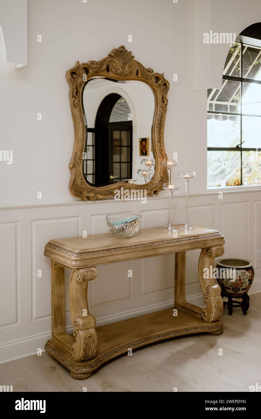 A brown table with objects in front of a mirror surrounded with white ...