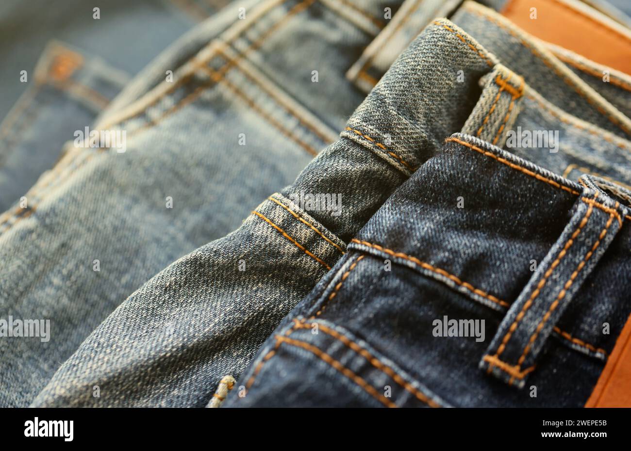 Many jeans in stack in wardrobe room. Row of pants denim jeans in ...