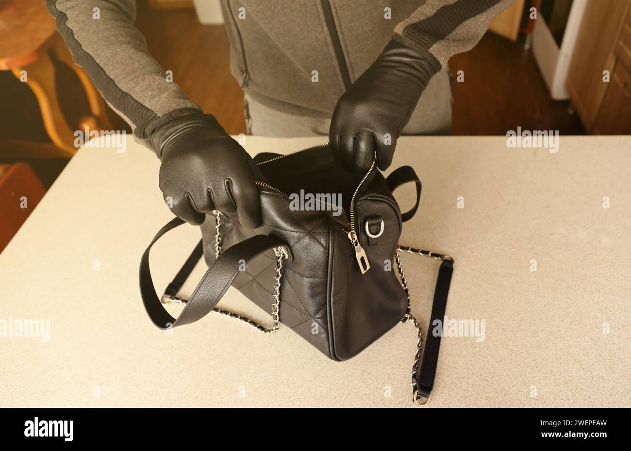 Robber in black outfit and gloves see on opened stolen women bag. A ...