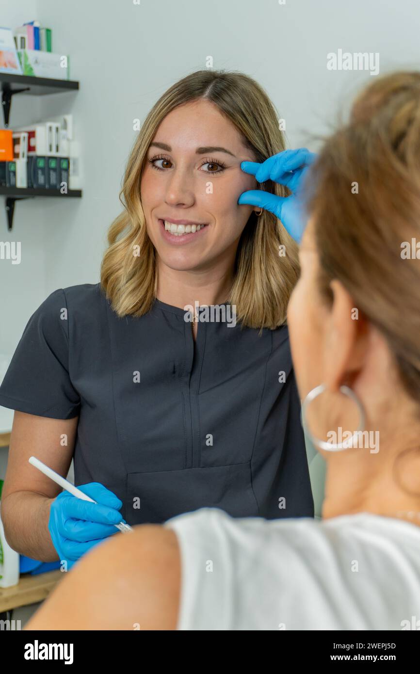 esthetician marks on her face the treatment she will do to client Stock ...