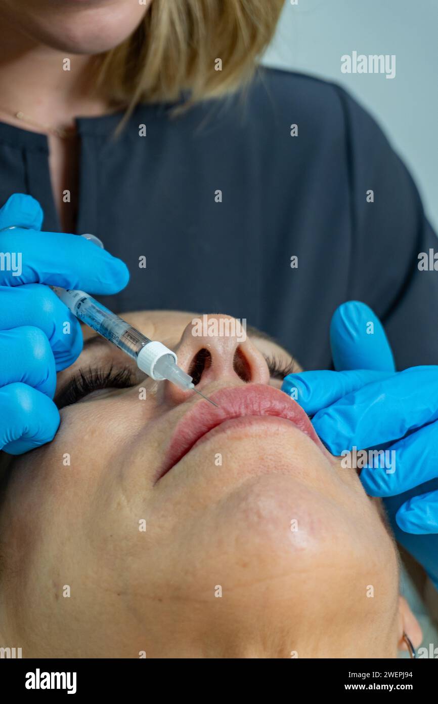 close-up of esthetician injecting botox into lips of an older woman ...
