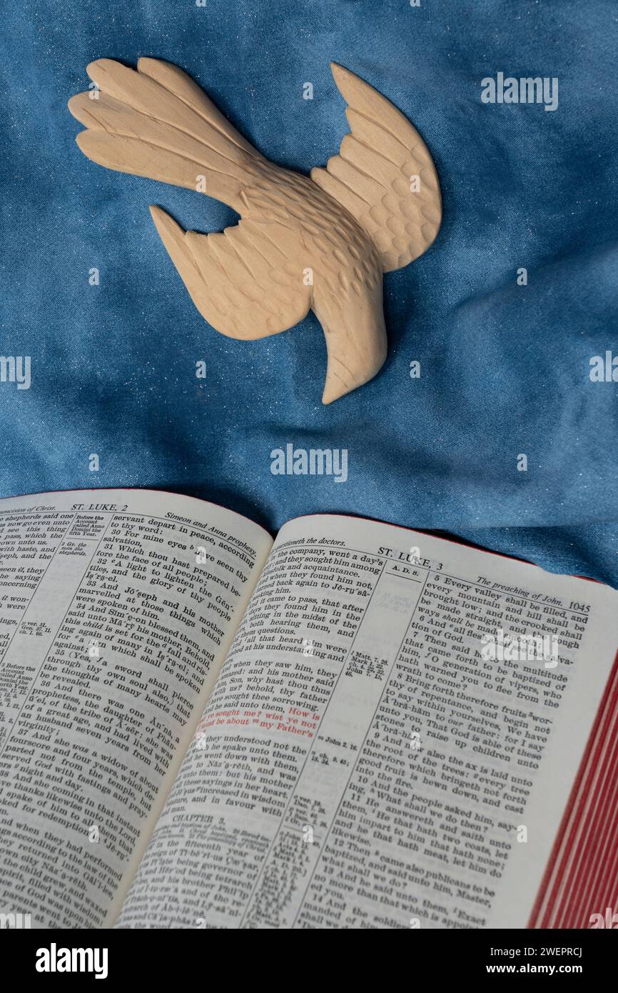 Holy Spirit figure descends on open Bible reading of St Luke. The dove ...