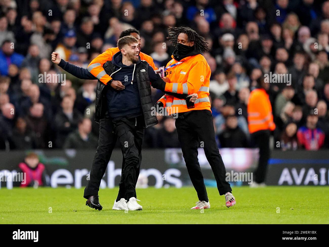A pitch invader is apprehended by match day stewards on the pitch ...