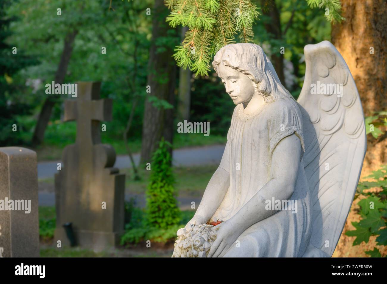 Mourning female statue at the tomb with stone cross in the background ...