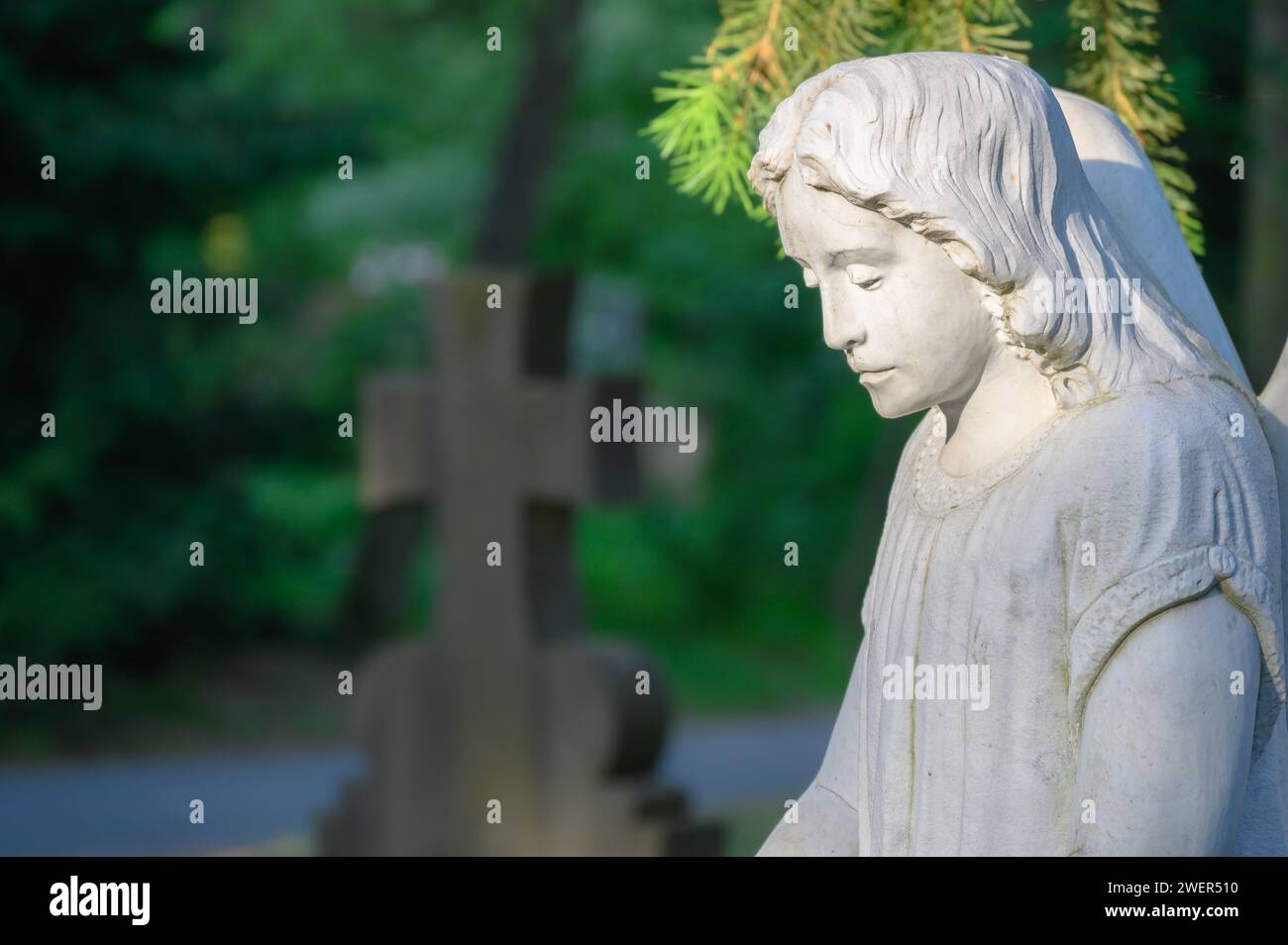 Mourning female statue at the tomb with stone cross in the background ...