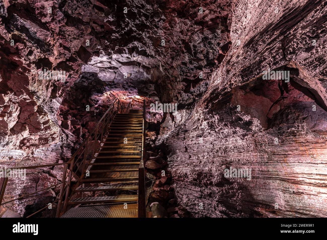 Purple illuminated rock structures and a staircase in the Raufarholshellir lava tunnel in ...