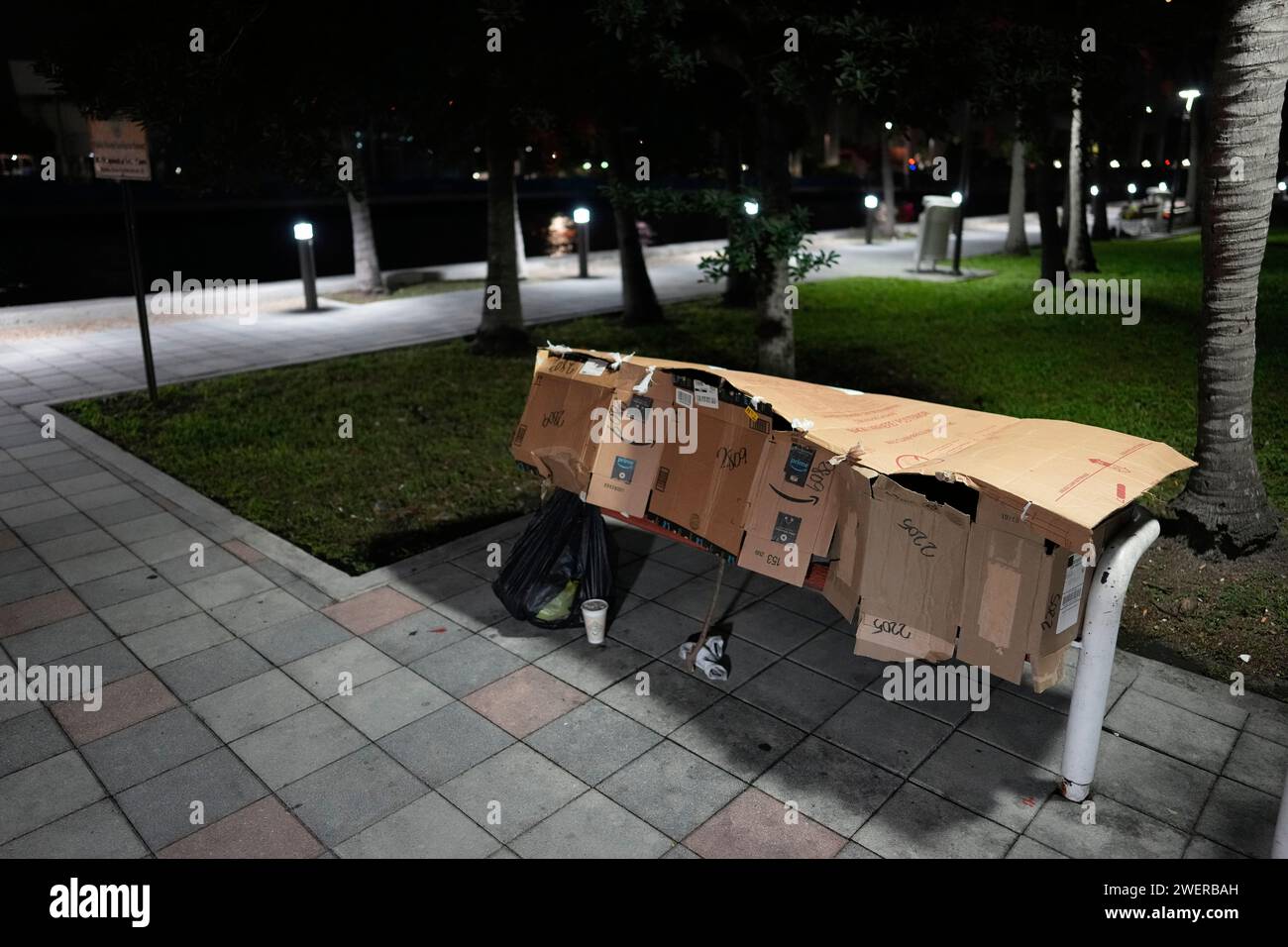 A person sleeps inside a makeshift shelter on park bench, as a team ...