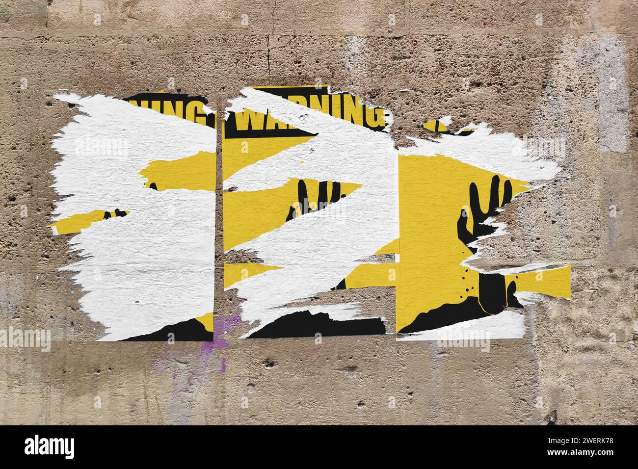 Full-frame weathered limestone wall with three torn yellow posters with ...