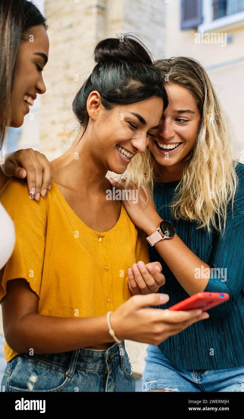 Three young beautiful women watching funny content on mobile phone app ...