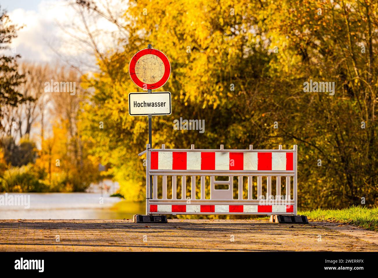 Backlight mood in sunshine with warning sign high water on a road on ...