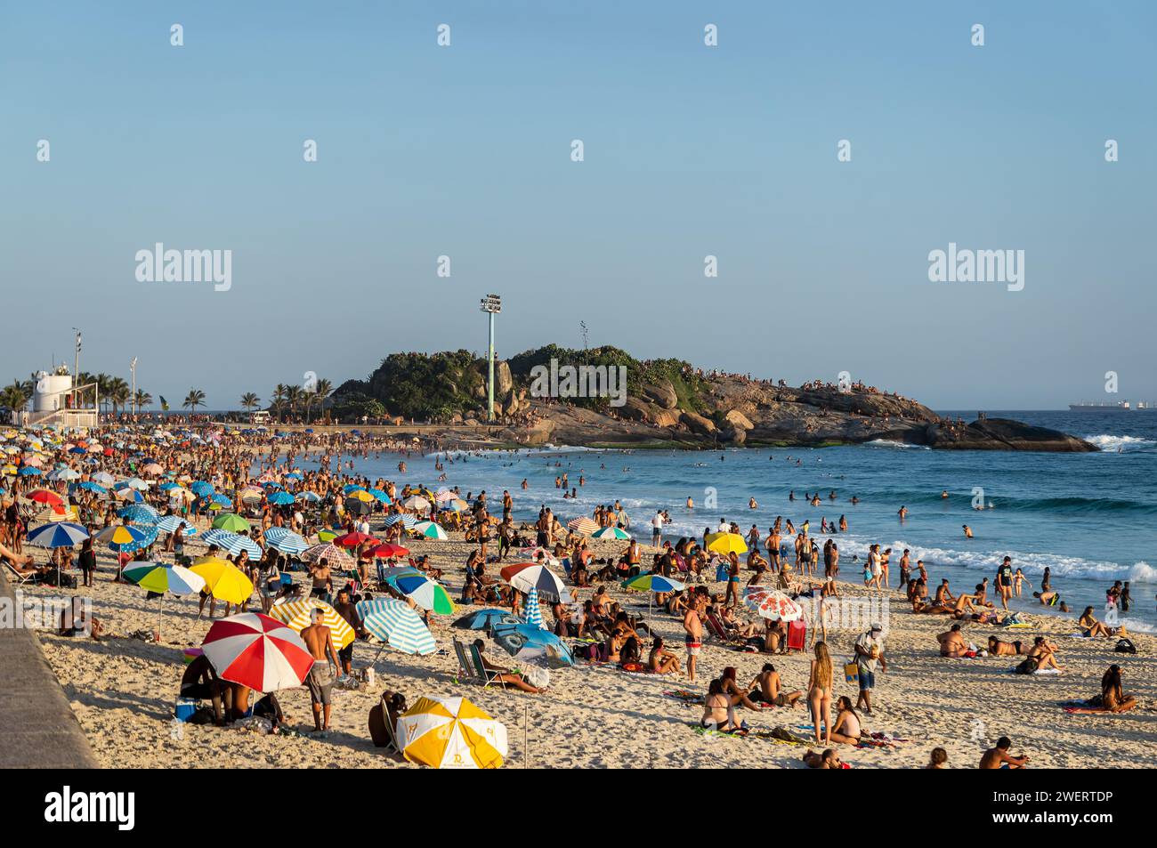 Heavily crowded Arpoador beach shoreline with Arpoador Rock (Pedra do ...