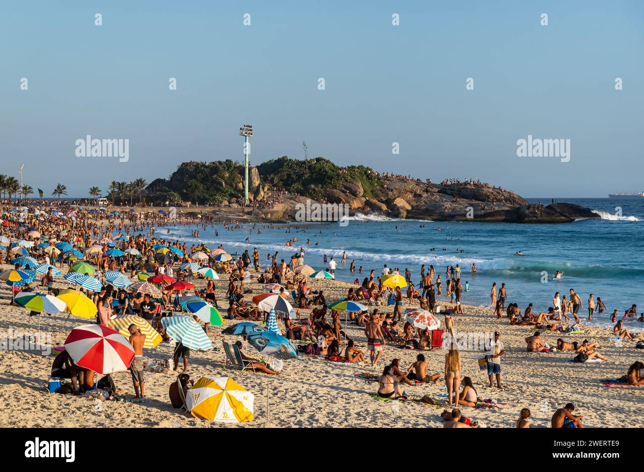Heavily crowded Arpoador beach shoreline with Arpoador Rock (Pedra do ...