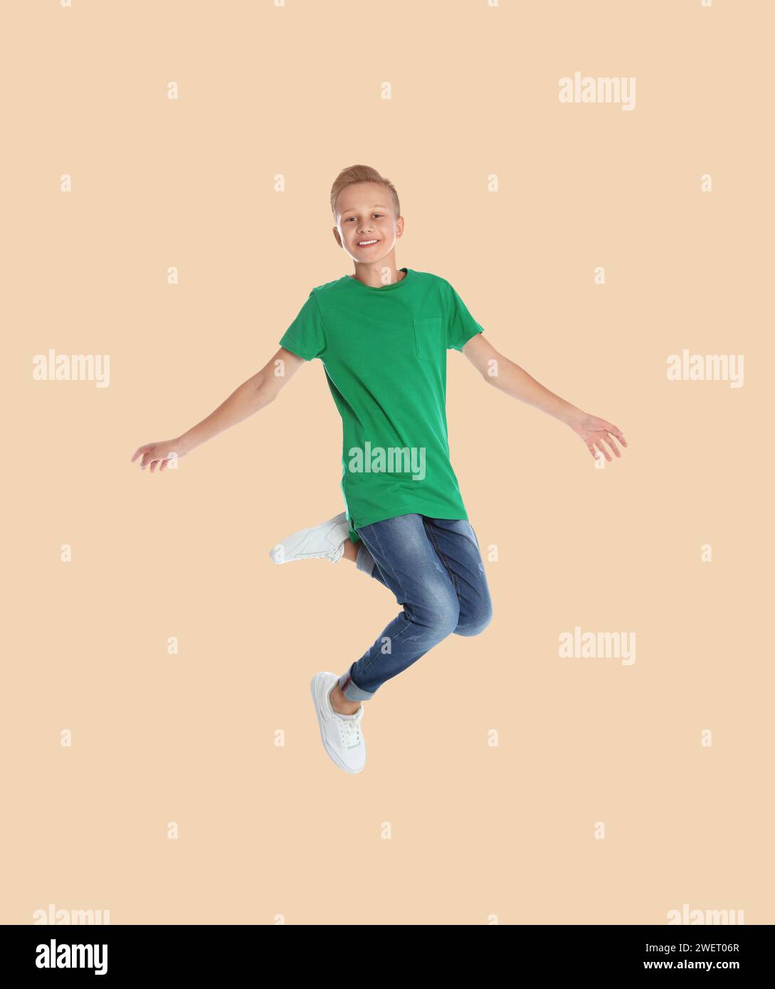 Teenage boy jumping on beige background, full length portrait Stock ...