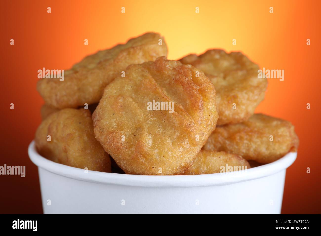 Bucket with delicious chicken nuggets on orange background, closeup ...