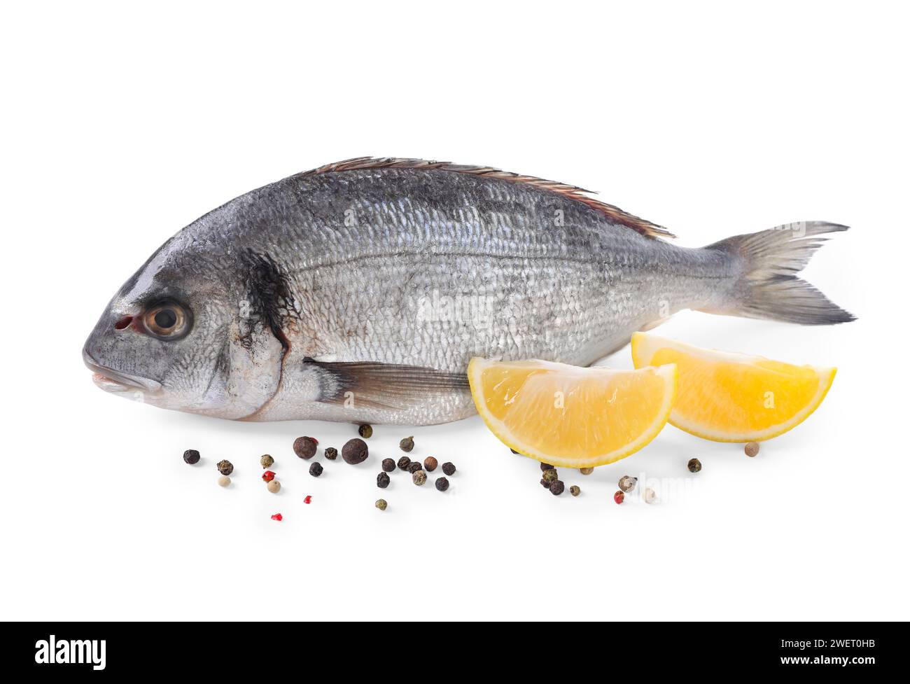 Raw dorado fish, lemon wedges and peppercorns isolated on white Stock ...