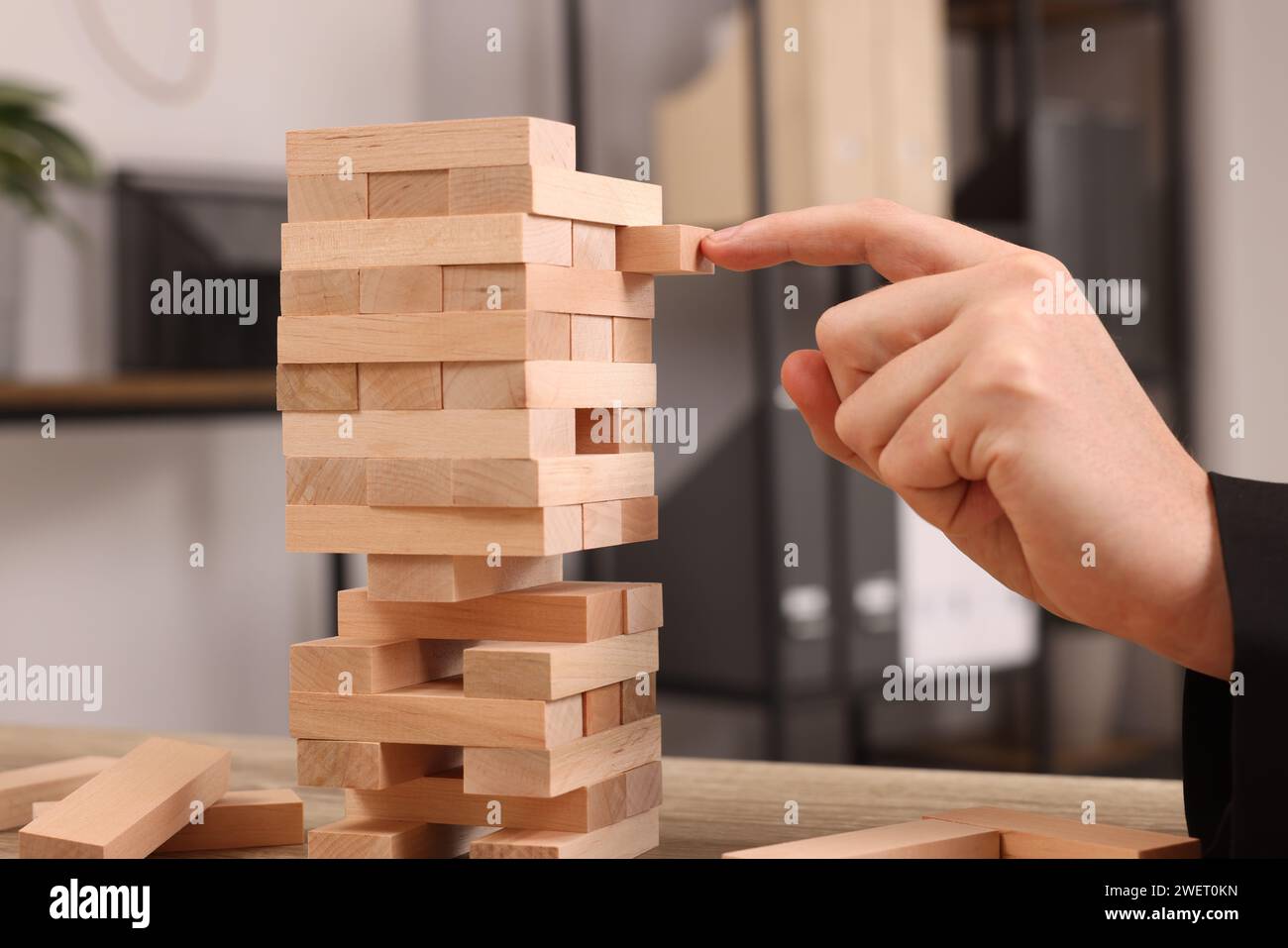 Playing Jenga. Man building tower with wooden blocks at table, closeup ...
