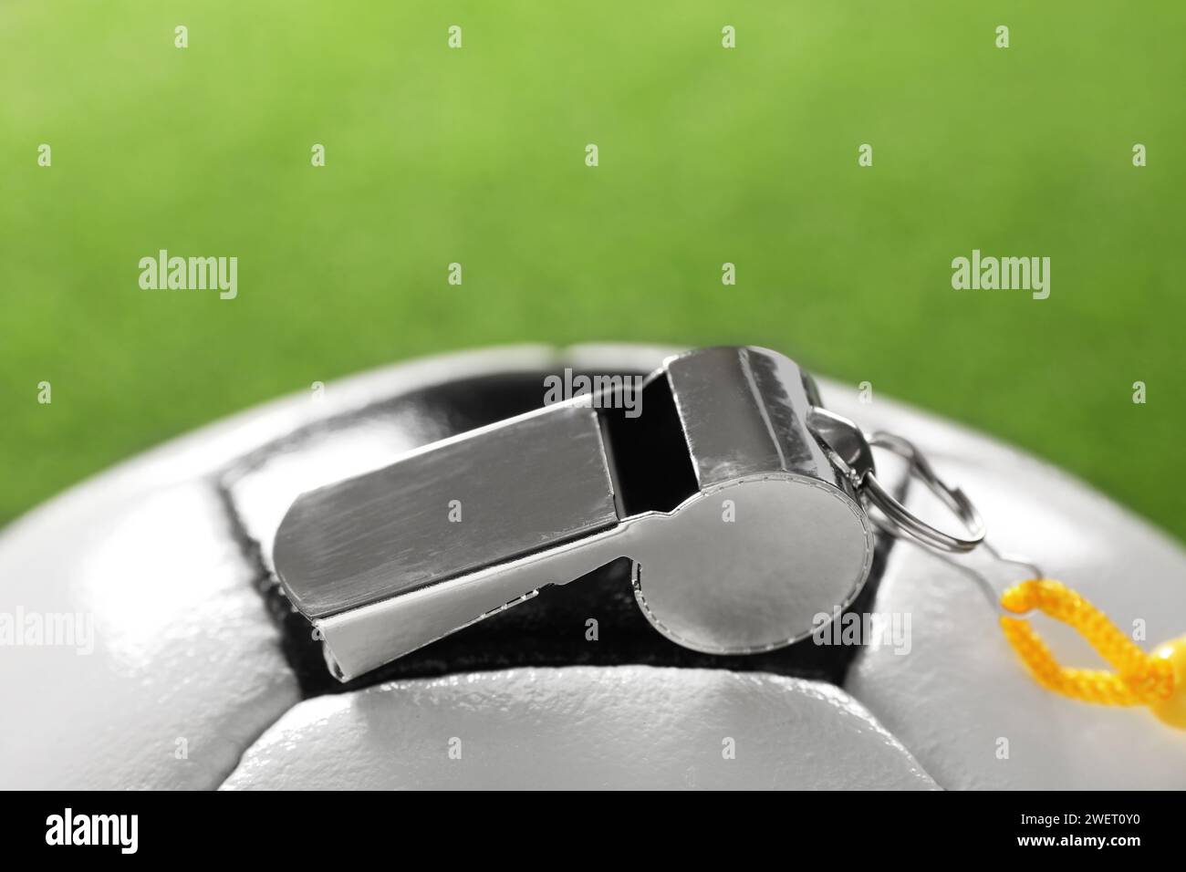 Football referee equipment. Soccer ball and metal whistle on green ...