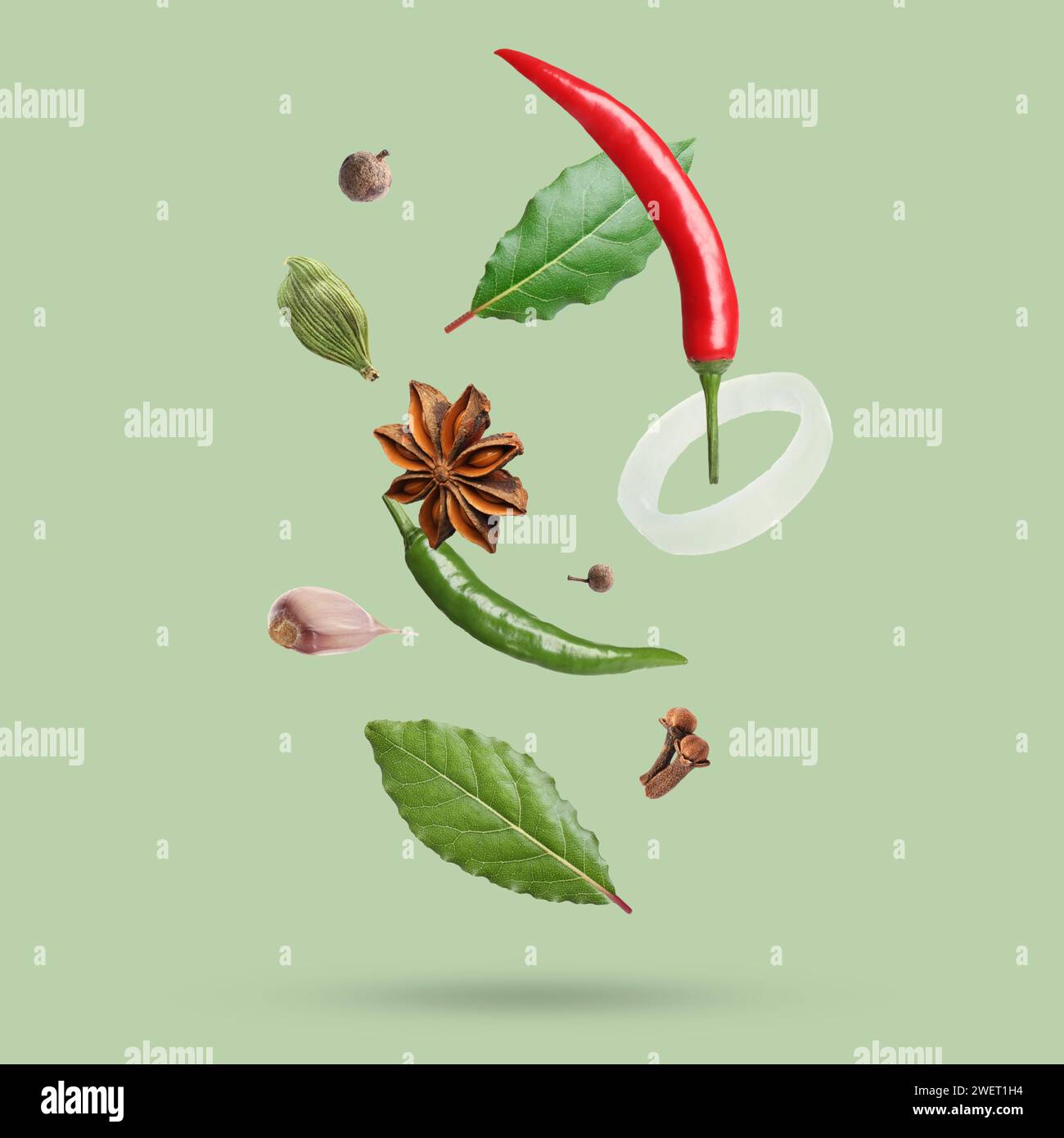 Different spices falling on light green background Stock Photo - Alamy