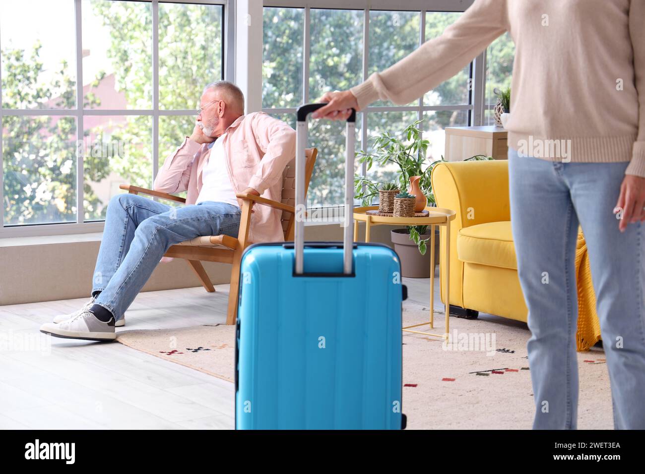 Mature woman with suitcase leaving her husband at home. Divorce concept ...