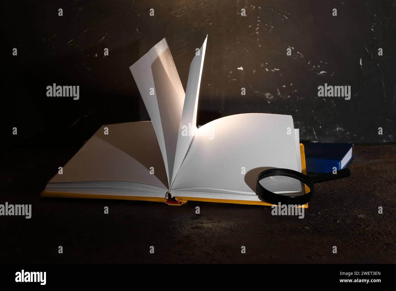 Open book with glowing light and magnifier on dark background Stock ...