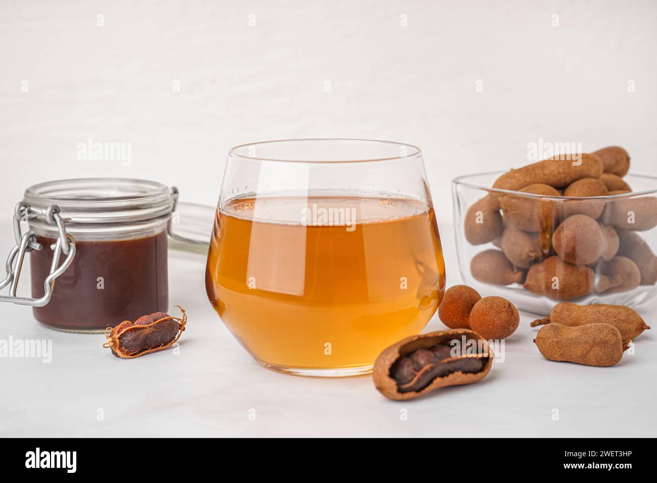 Glass of tasty tamarind drink with jam and fruits on white background ...