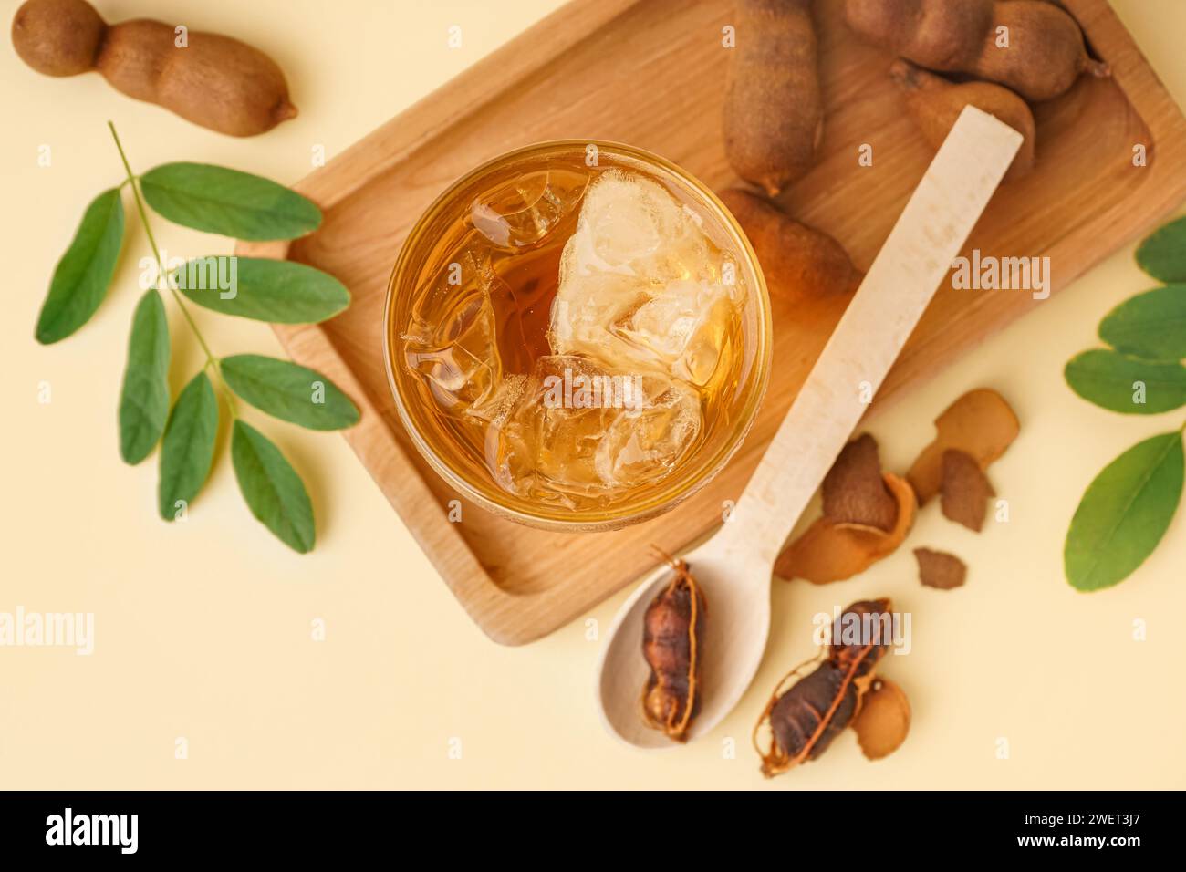 Glass of tasty tamarind drink and fruits on yellow background Stock ...
