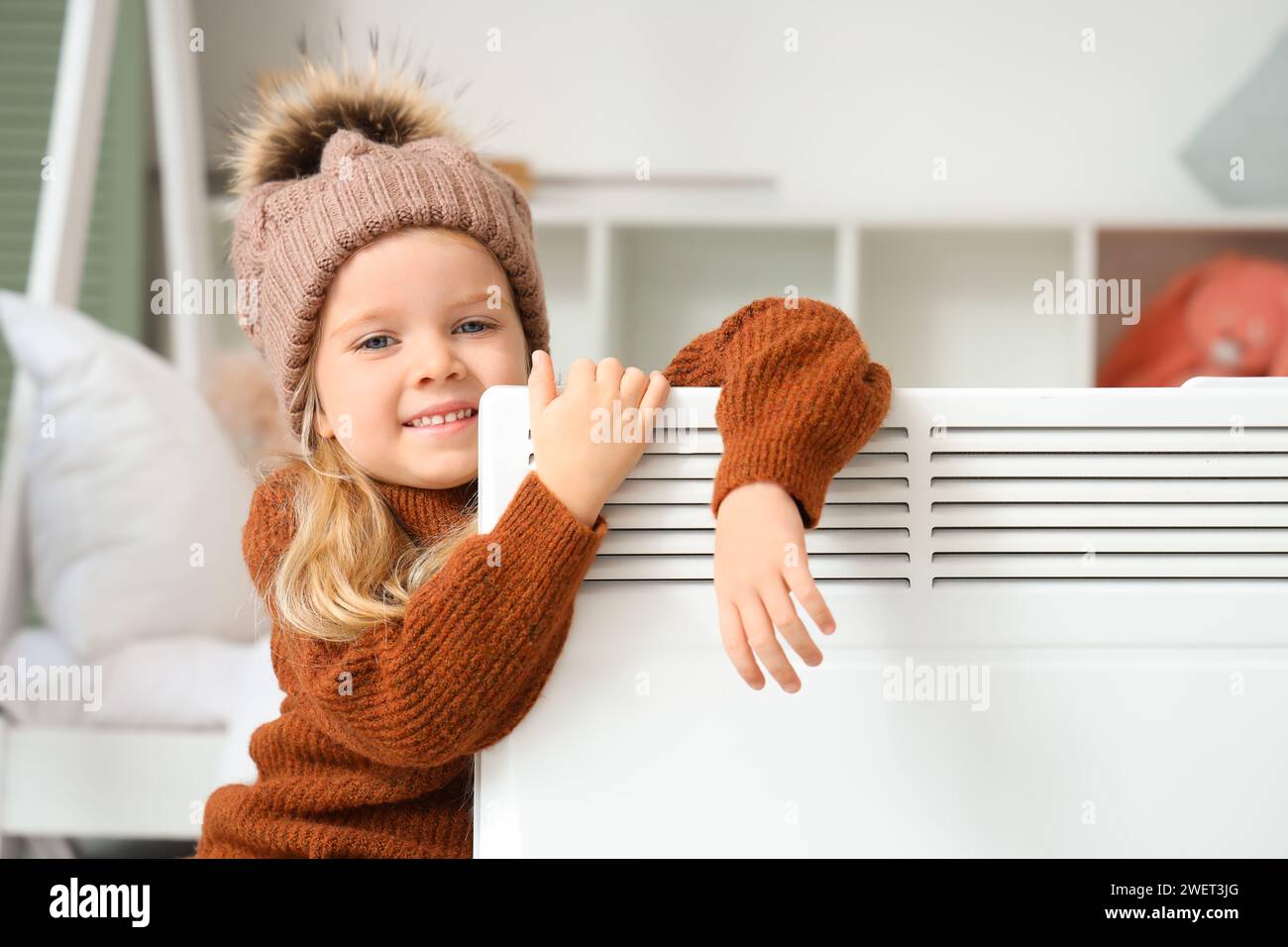 Cute little girl warming near radiator in bedroom, closeup Stock Photo ...