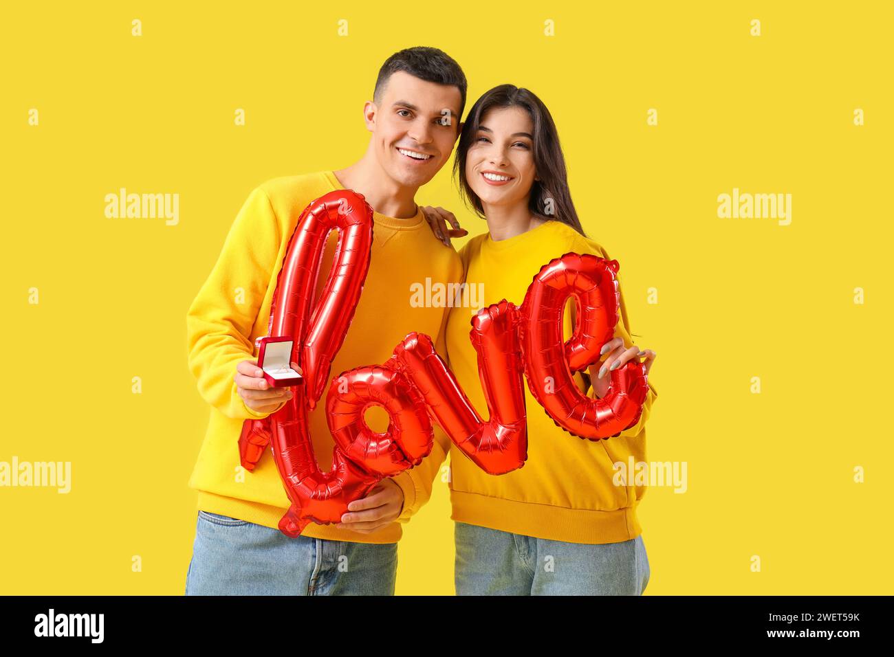 Young engaged couple with wedding ring and word LOVE made from balloons ...