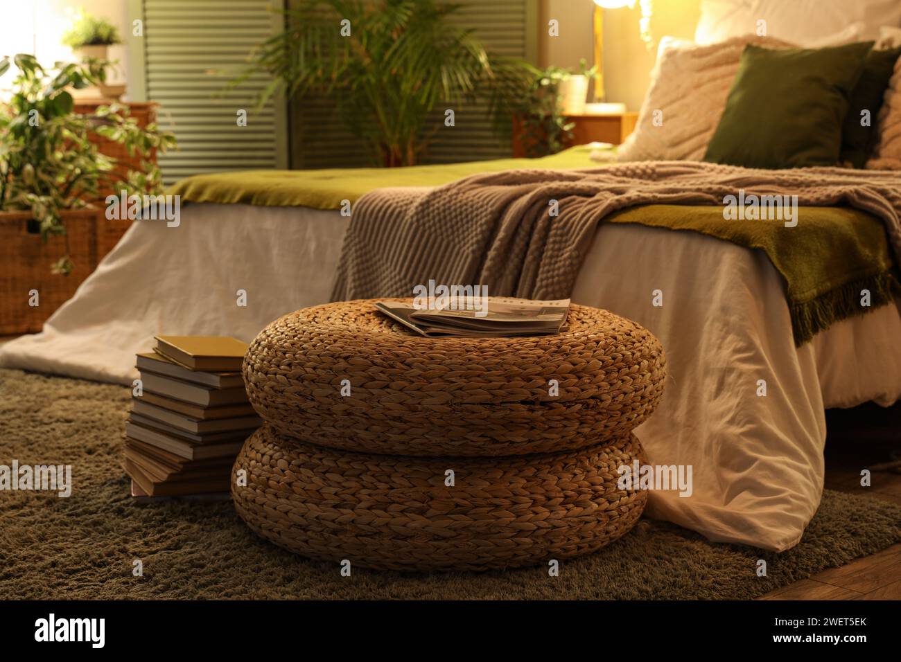 Interior of stylish bedroom with blankets on bed, wicker poufs and ...