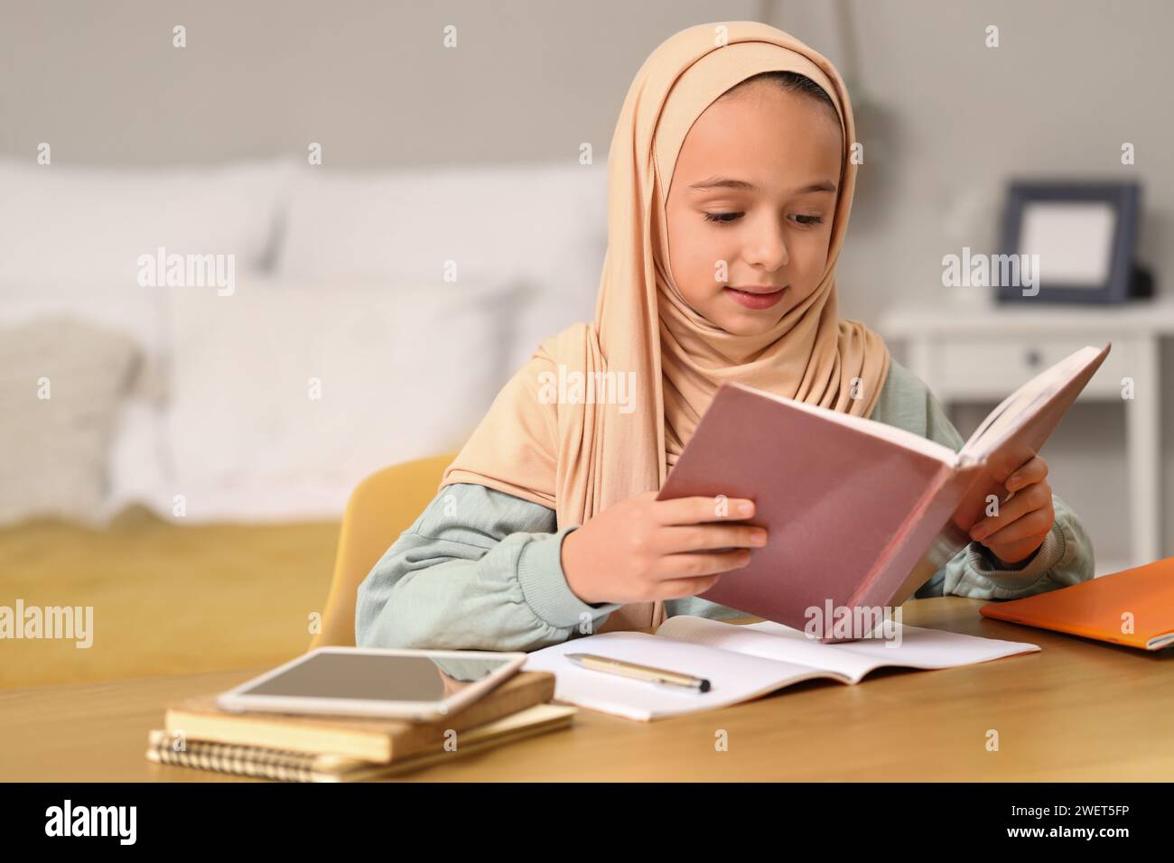Little Muslim girl in hijab doing homework at home Stock Photo - Alamy
