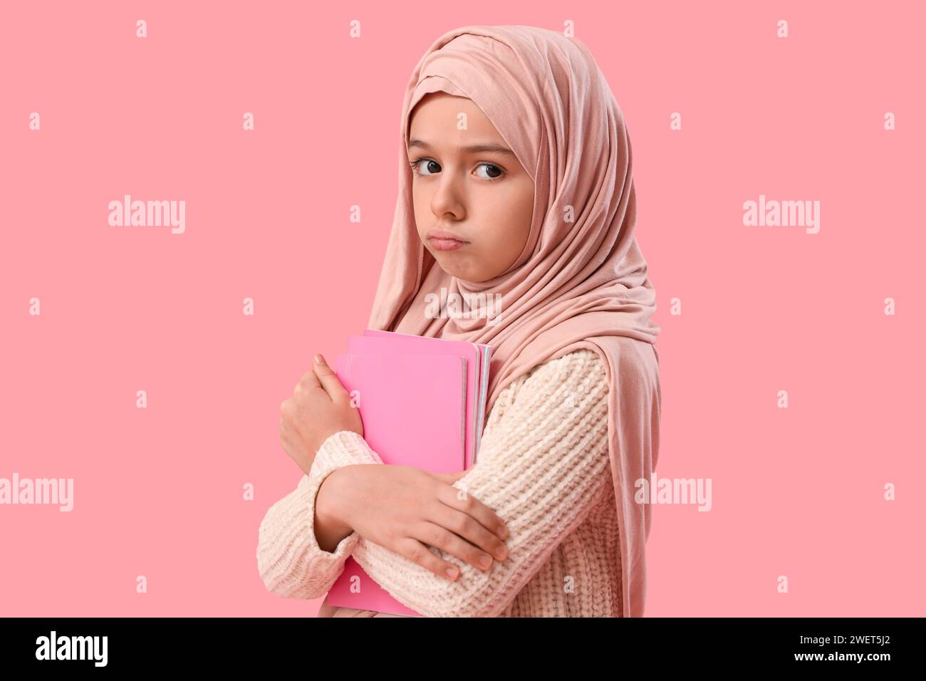 Sad Muslim girl in hijab holding copybooks on pink background Stock ...