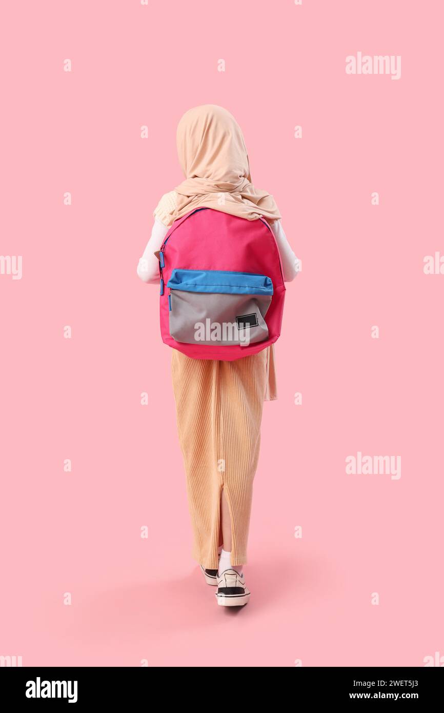 Little Muslim girl in hijab with school backpack on pink background ...