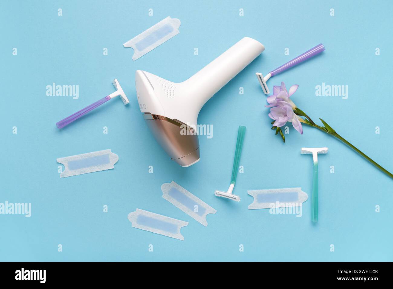 Modern photoepilator with wax strips, razors and beautiful flower on ...