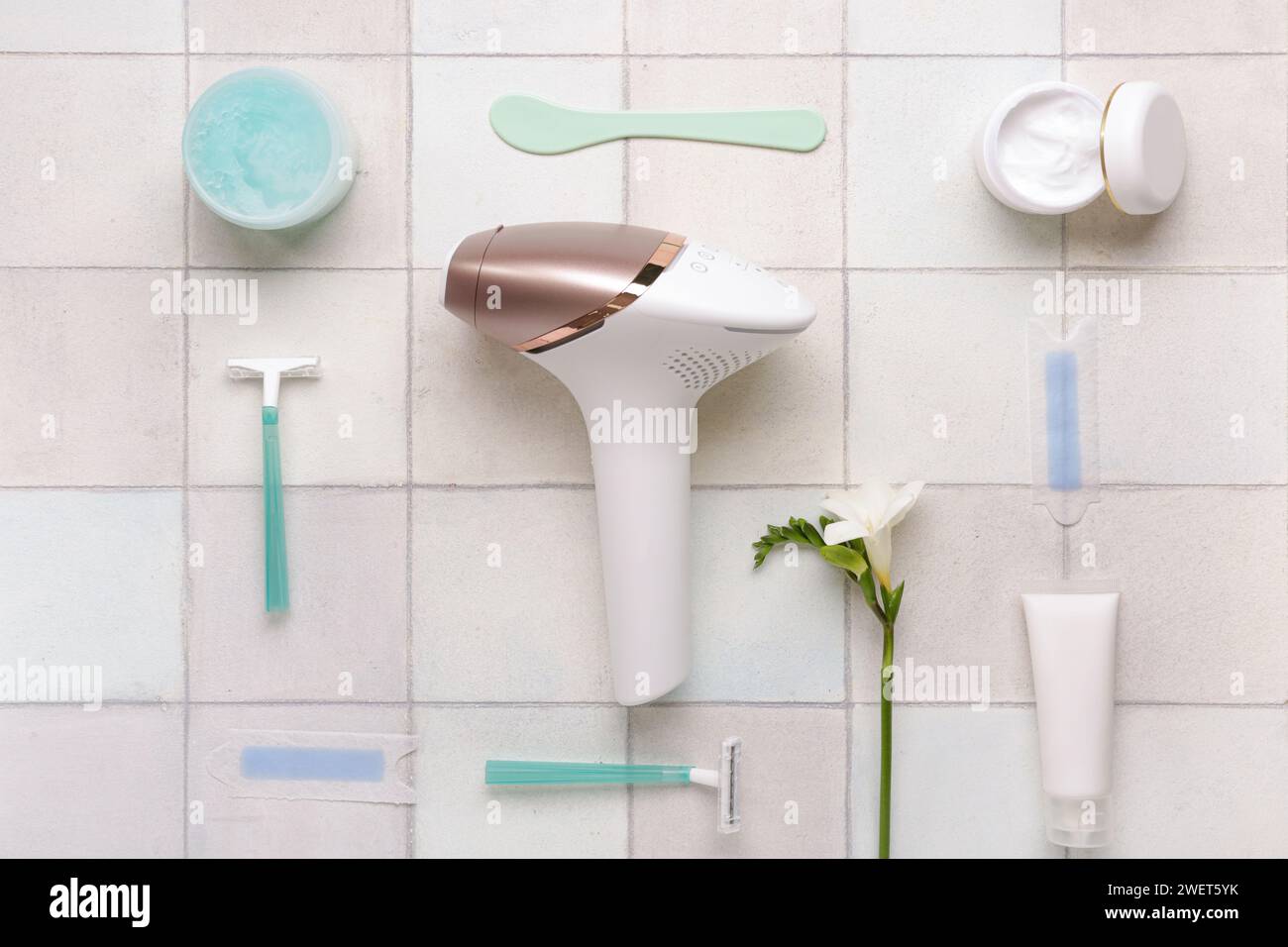 Modern photoepilator with cosmetic products, wax strips and razors on ...