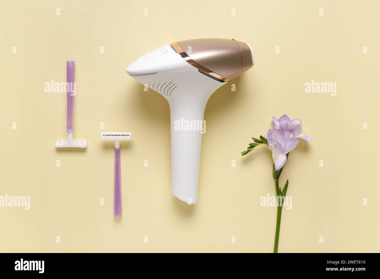 Modern photoepilator with razors and flower on yellow background Stock ...