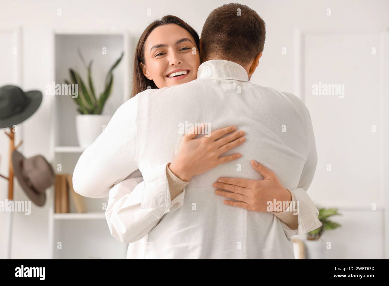 Happy young woman hugging her husband at home Stock Photo - Alamy